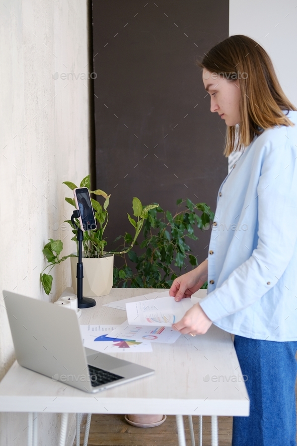Serious young woman holding graphs and charts and leading business ...