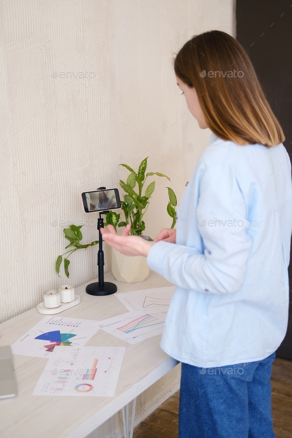 Young woman holding graphs and charts and leading business meeting ...