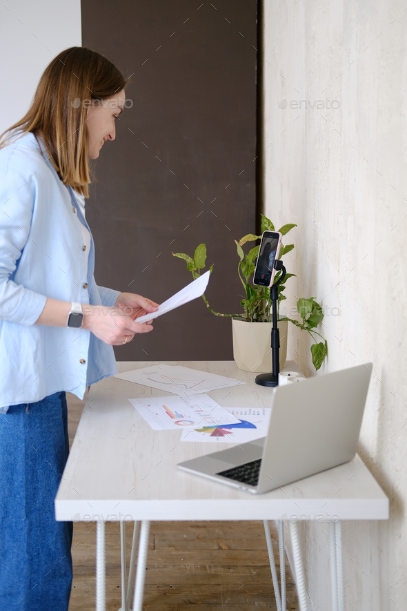 Joyful young woman holding graphs and charts and leading business ...