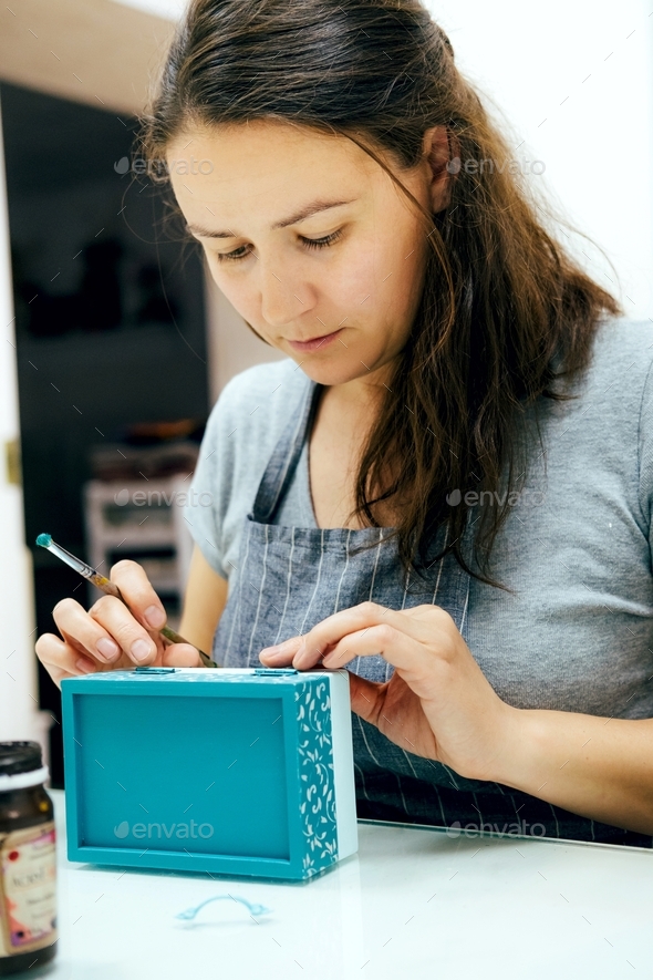 Woman Artist craftsman works in creative workshop and decorates box ...