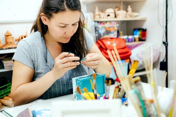 Woman Artist craftsman works in creative workshop and decorates box ...