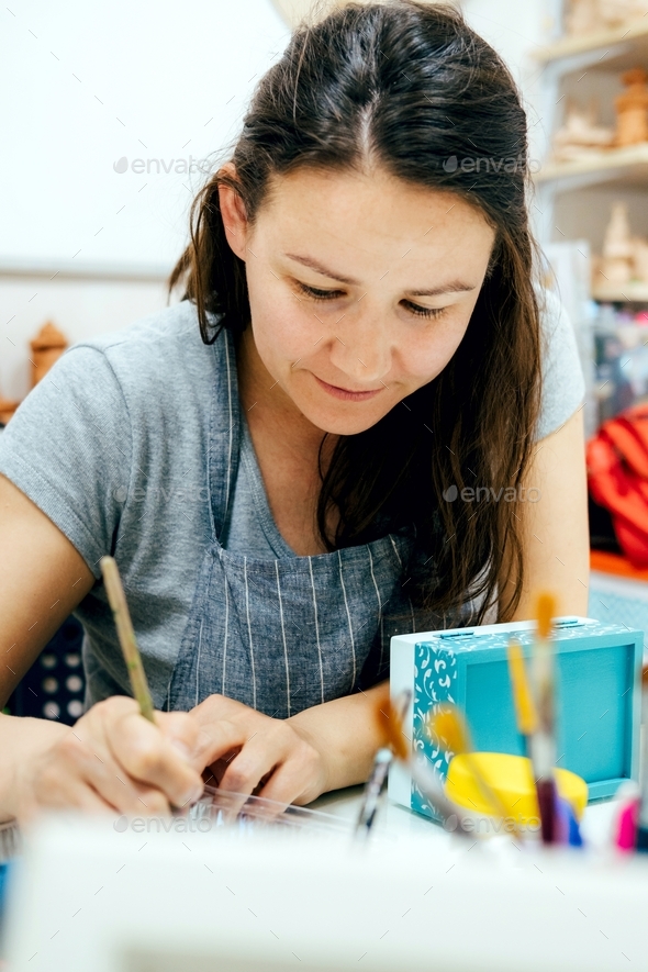 Woman Artist craftsman works in creative workshop and decorates box ...