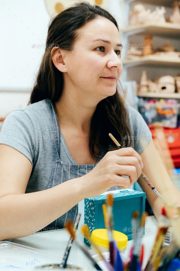 Woman Artist craftsman works in creative workshop and decorates box ...