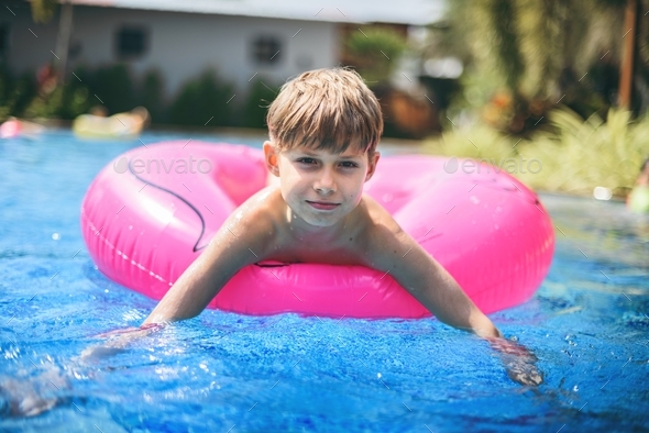 Boy on floating toy inflatable ring in blue water. Swimming pool Stock ...