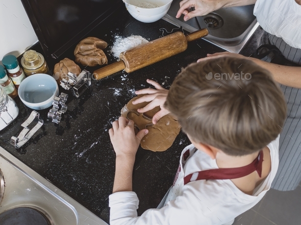 Cooking. Young boy is shaping and cutting rolled dough on the table to ...
