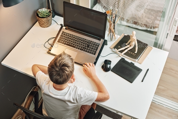 Overhead workspace. Boy is on the online lesson. Concept of new normal ...