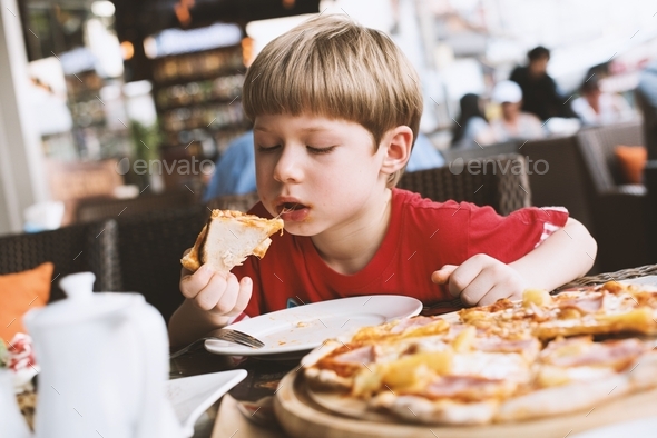 Cute child boy bringing pizza slice up to his mouth to eat.Kids love ...