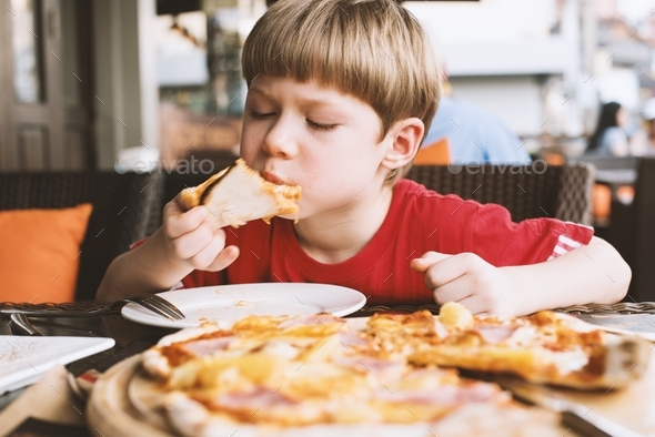Cute child boy bringing pizza slice up to his mouth to eat.Kids love ...
