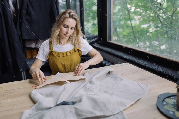 Young dressmaker pinning fabric cutouts in workshop. Copy space. Stock ...