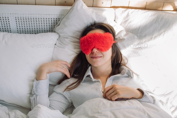 Woman in fluffy red heart shape sleep mask laying in bed. Valentine’s ...
