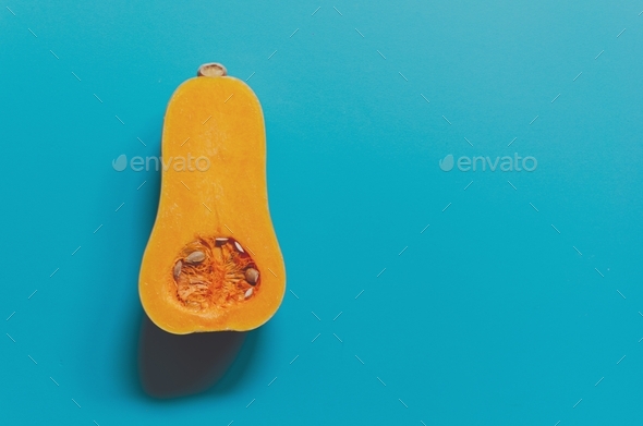 Winter butternut squash gourd sliced in half on a blue background with ...
