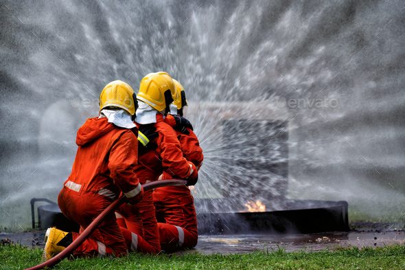 fire fighter team on training with gas and oil fire hold hose spray jet ...