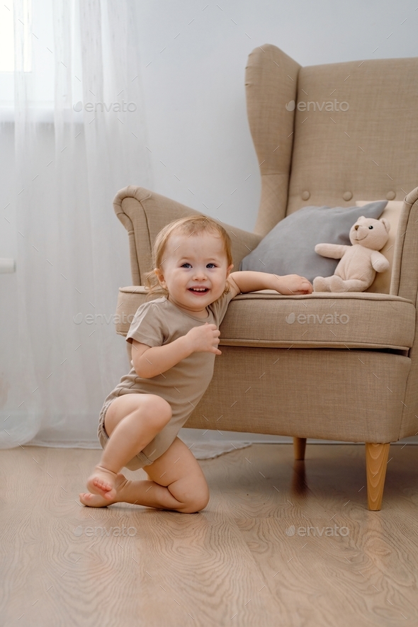 A cute baby learning to stand up with support. A smiling toddler ...