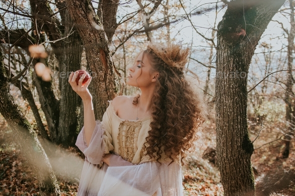 Curly haired princess girl eating an apple in the sunset Stock Photo by ...