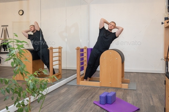 Male fitness Pilates trainer shows exercises on special simulators ...