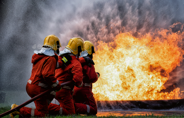 fire fighter team on training with gas and oil fire hold hose spray jet ...