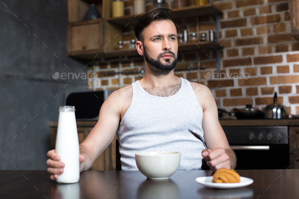 handsome young man pouring milk from bottle at breakfast Stock Photo by ...