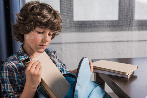 side view of caucasian little boy packing backpack for school Stock ...