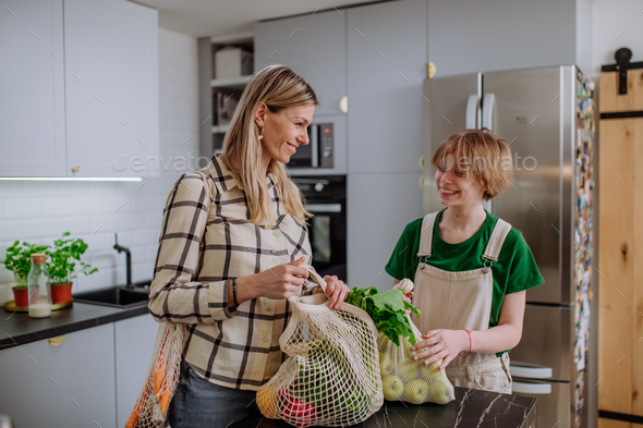 Mother unpacking local food in zero waste packaging from bag with help ...