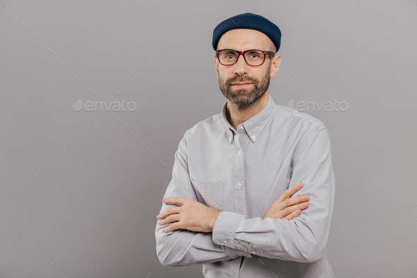 Photo of serious male keeps arms folded over chest, dressed in white ...