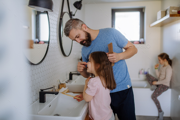 Father brushing his little daughter's hair in bathroom, morning routine concept. Stock Photo by ...