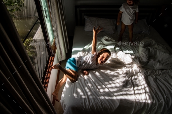 waking up from a dream. small children play in the bed in the sunlight ...