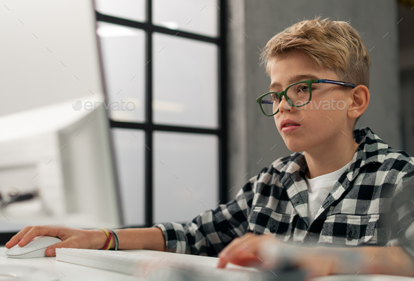 Schoolboy using computer in classroom at school Stock Photo by halfpoint