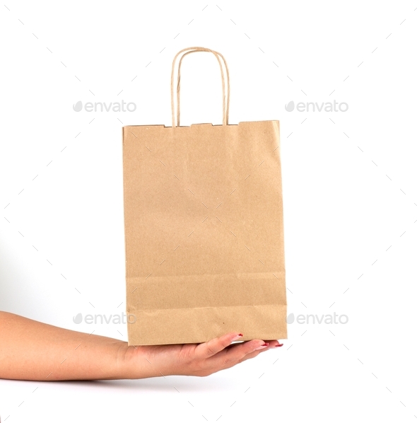 Female hand holding a paper bag on the palm, isolated on the white ...