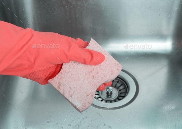 Sink drain and hand wearing orange rubber glove cleaning scrub steel ...