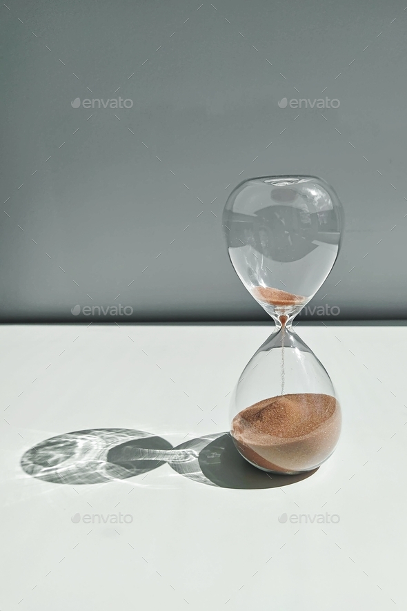 Glass sandglass on white table on gay background Stock Photo by Kira_Yan