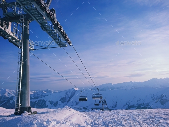 View of ski lift at ski resort with gorgeous snowy peaks at sunset ...