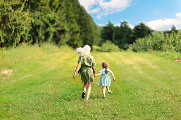 Mom and daughter are walking in the apple orchard in spring. Family on ...