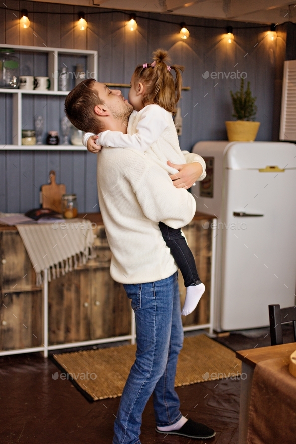 Dad and daughter in the kitchen. Father's day. Daddy hugs a little girl. Family relationships ...