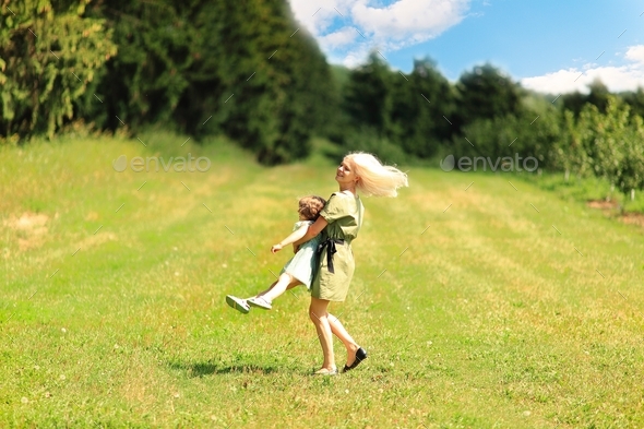 Mom and daughter are walking in the apple orchard in spring. Family on ...