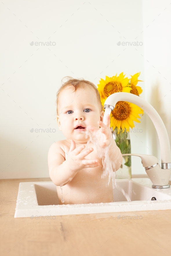 Baby taking bath in kitchen sink. Little boy bathing. Water fun for ...