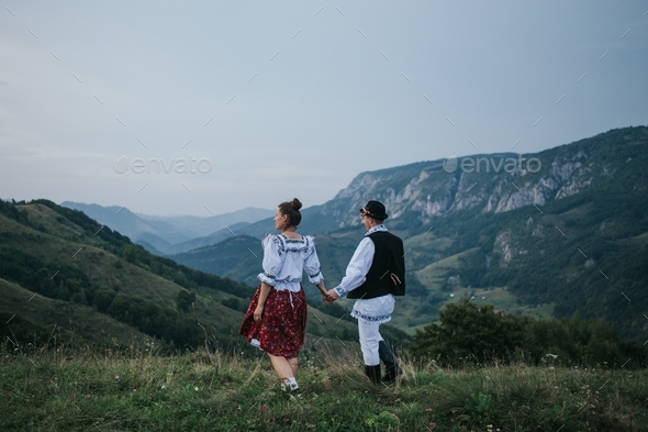 Young couple dressed in traditional costumes holding hands and walking ...