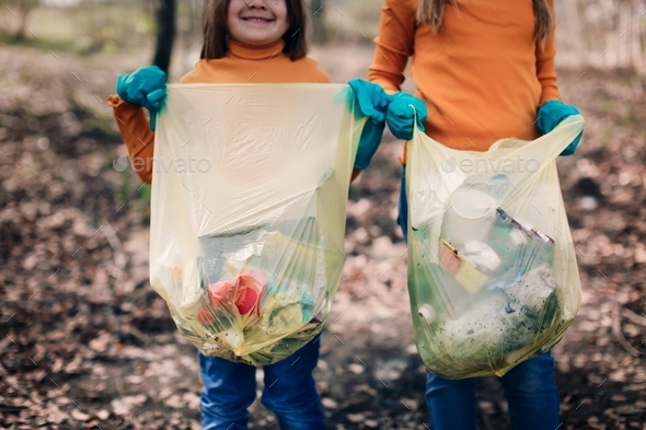 happy kids with full garbage bags in the park. Two children collect ...