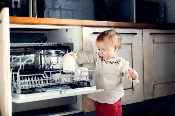child toddler unloads the dishwasher on his own in a Scandinavian-style ...