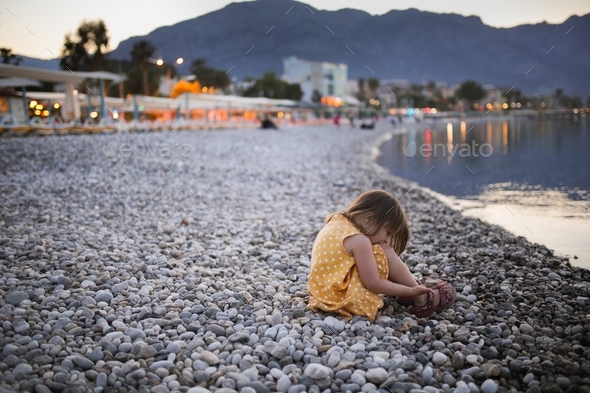 Sad little girl child by the sea on a pebble beach, children's emotions ...