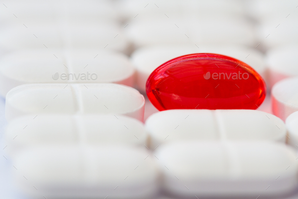 single red capsule standing out against rows of white pain relief ...