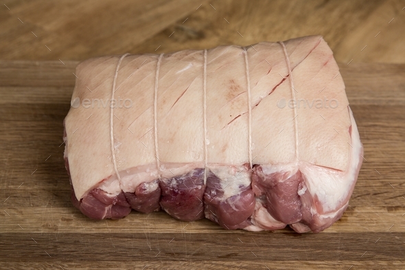 A raw shoulder of pork cut of meat with pig skin scored by a butcher ...