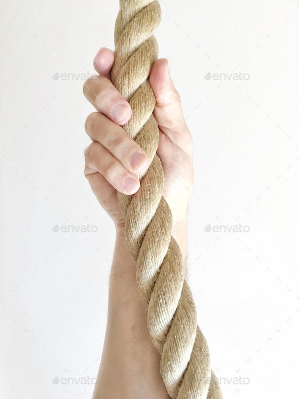 a male hand and arm pulling on a thick rope like a bell ringer or tug ...