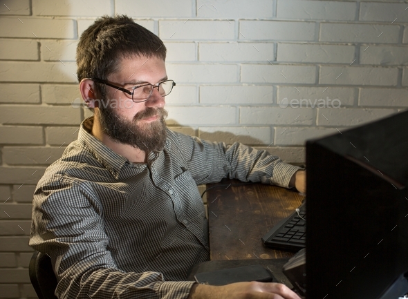 a man with a beard is sitting in glasses at a computer in front of a ...