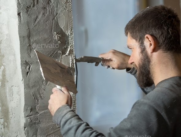 a man with a beard plasterer mounts a perforated painting corner on the ...