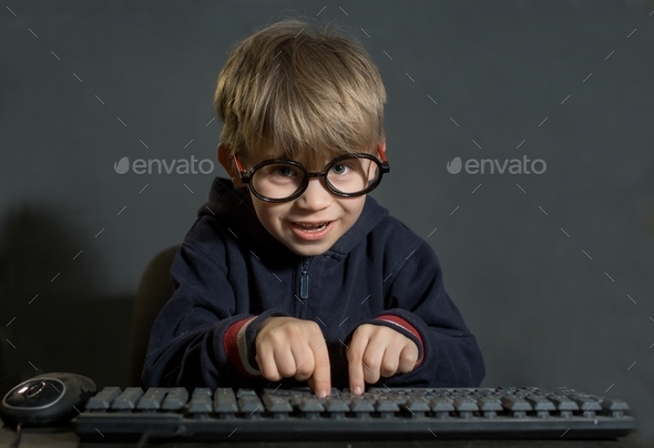 the boy is learning to use the computer, he is sitting with a tense ...
