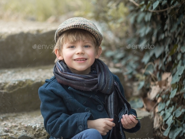 a little boy in a vintage coat and cap is walking on the street Stock ...