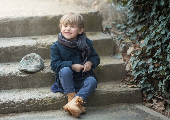 a little boy in a vintage coat and cap is walking on the street Stock ...