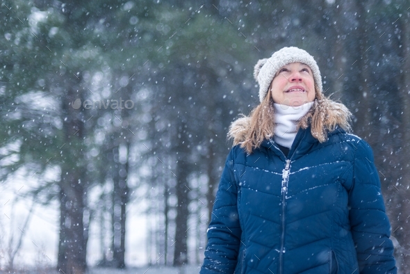Smiling Woman looking up at falling snow Stock Photo by davidprahl