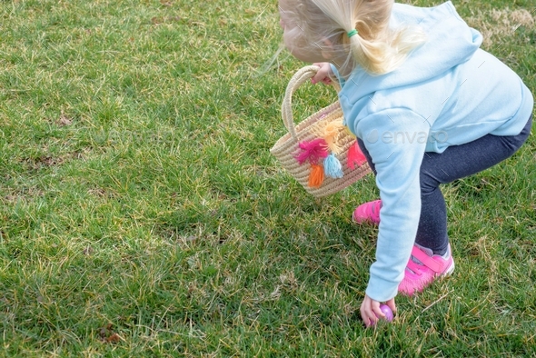 Little girl running and picking up plastic egg at Easter egg hunt Stock ...