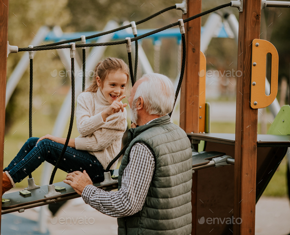 Grandfather spending time with his granddaughter in park playground on ...